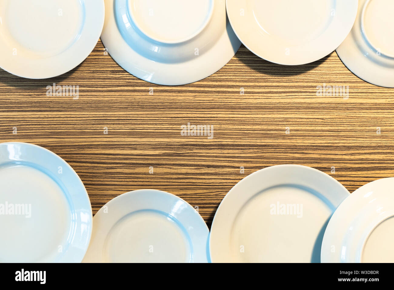 Empty white plates on wooden table Stock Photo - Alamy