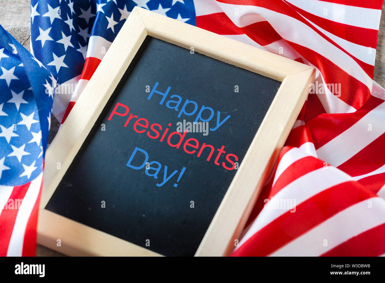 the text happy presidents day written in a chalkboard and a flag of the ...