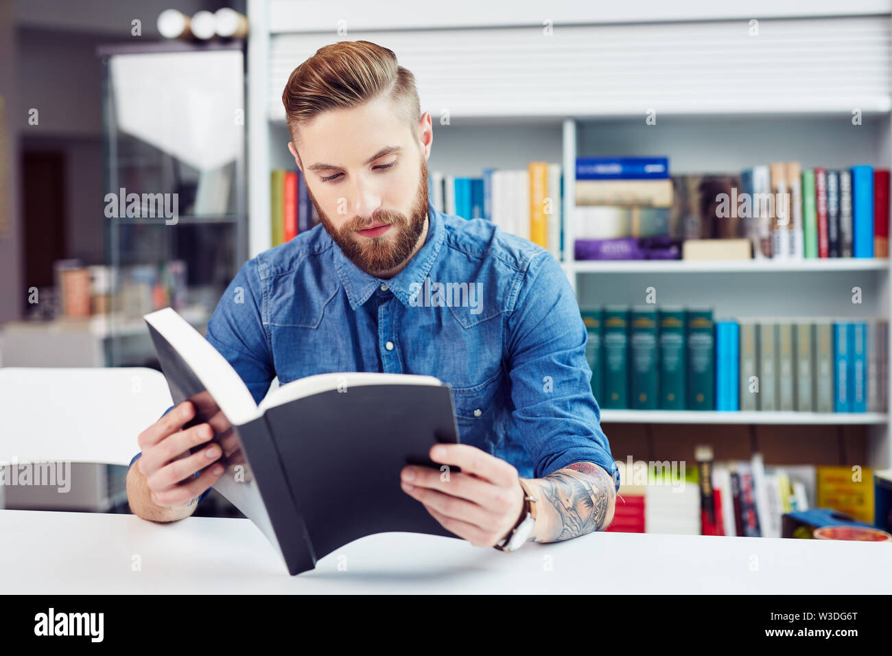 Studying for an exam. Focused handsome young man studying from textbook ...