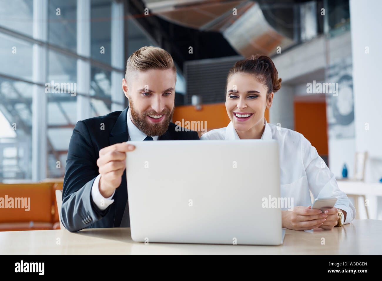 Two happy business people working on laptop at office Stock Photo - Alamy