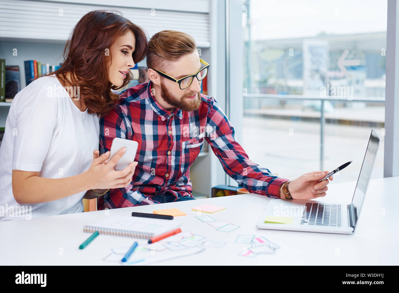 Web designers working on laptop at office Stock Photo - Alamy