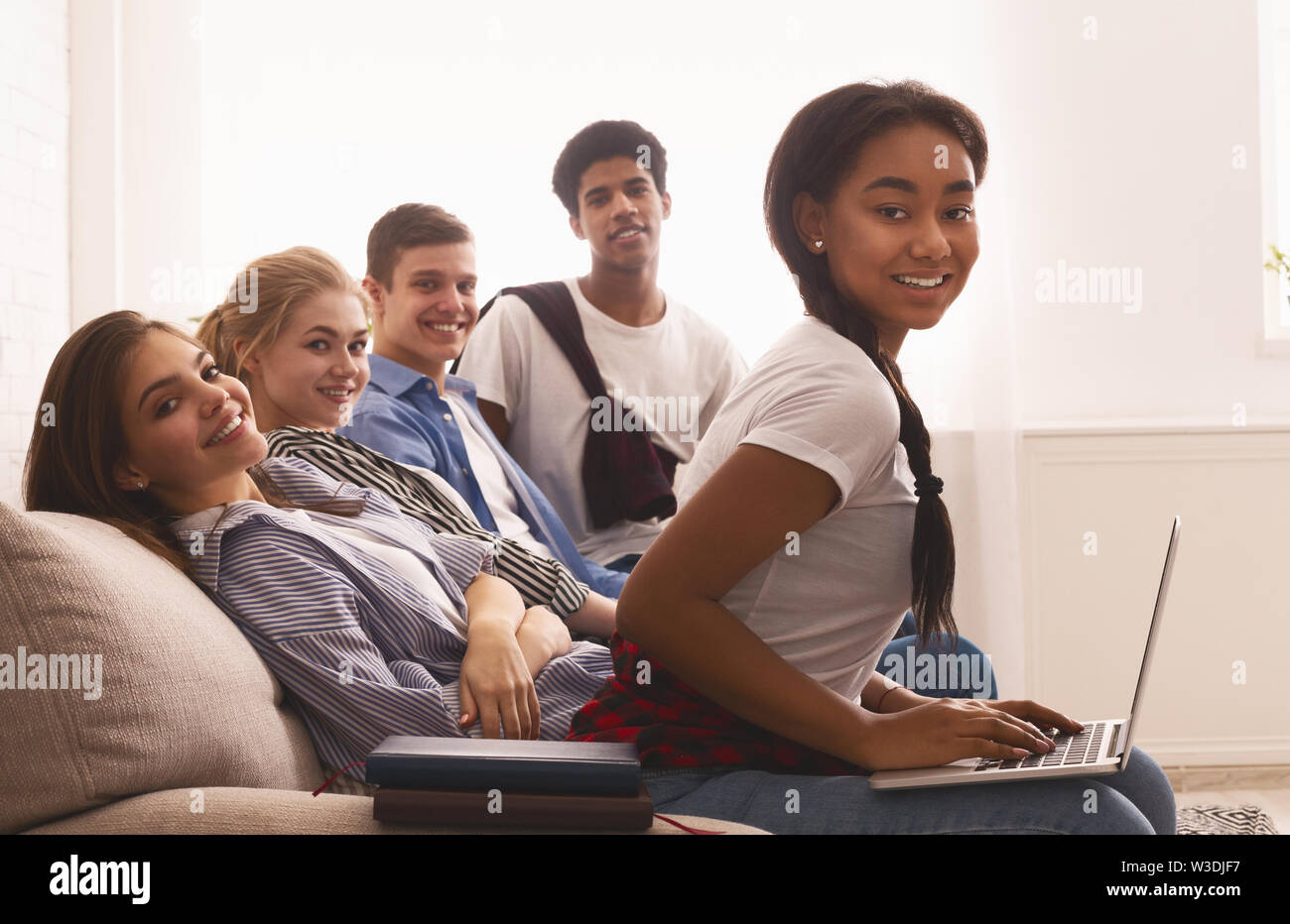 College classmates resting with books and laptop on sofa Stock Photo ...