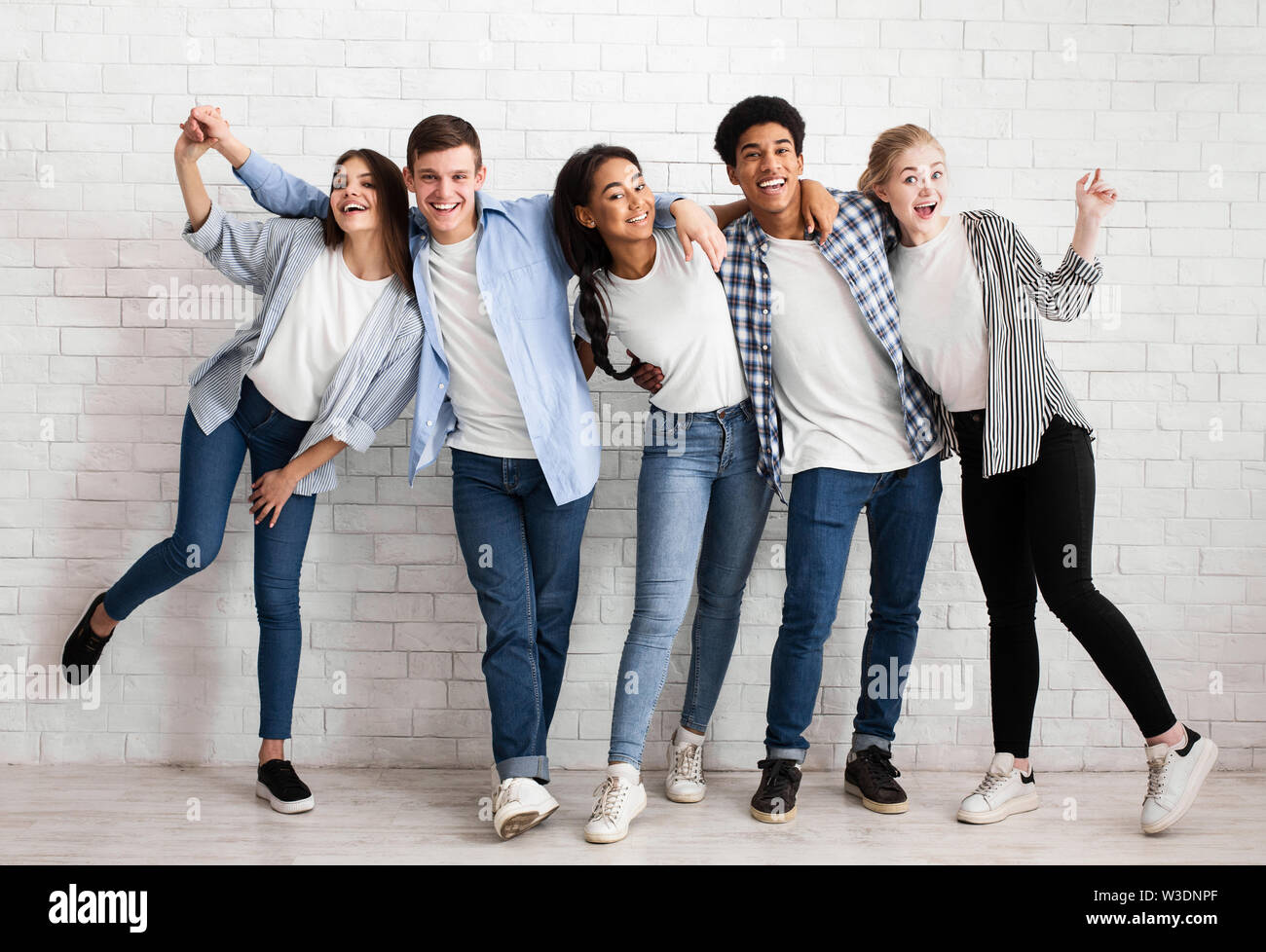 Friends embracing and having fun over white brick wall Stock Photo - Alamy