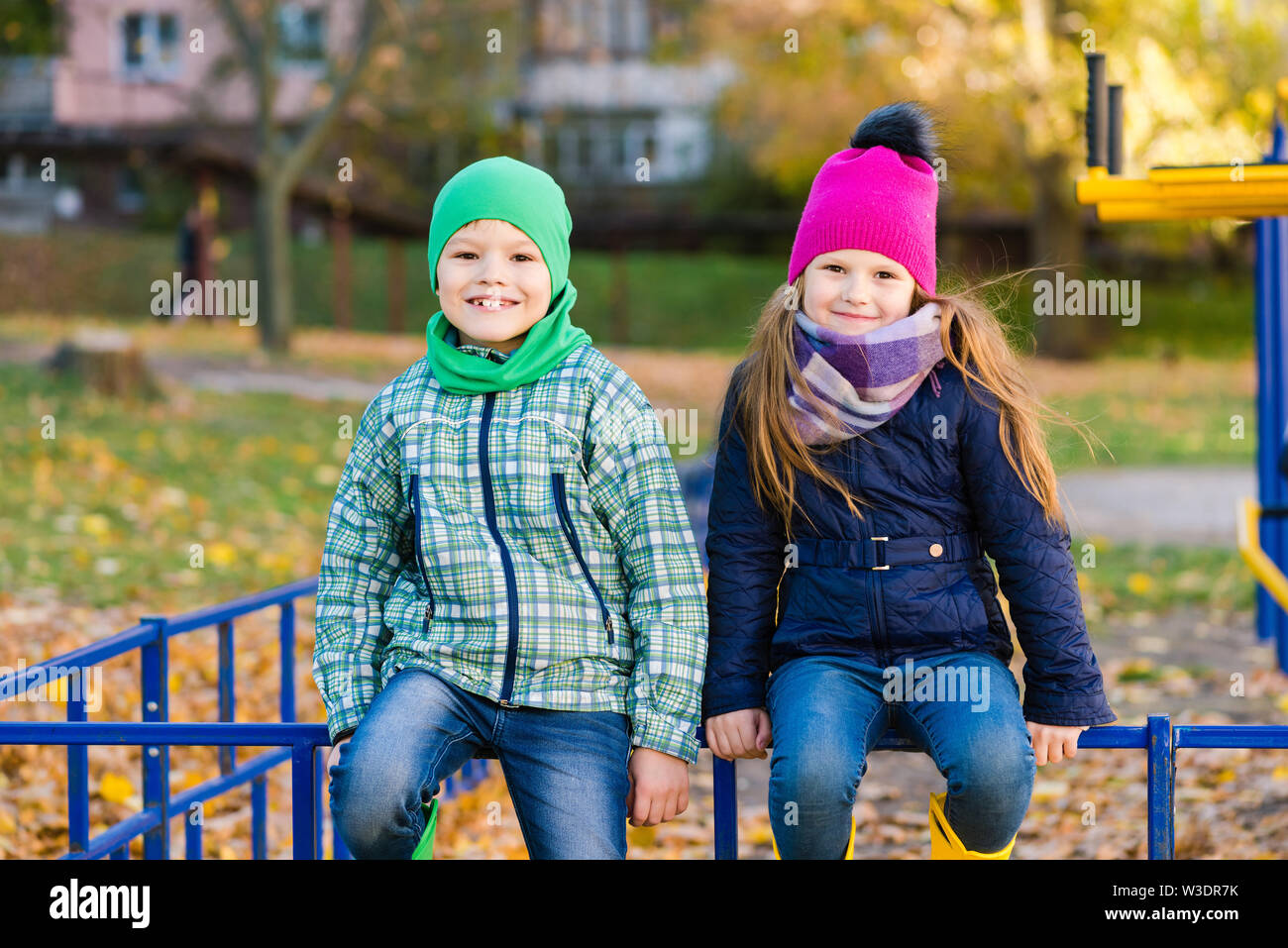 Two happy children in autumn clothes smiling outdoors. Boy and girl ...