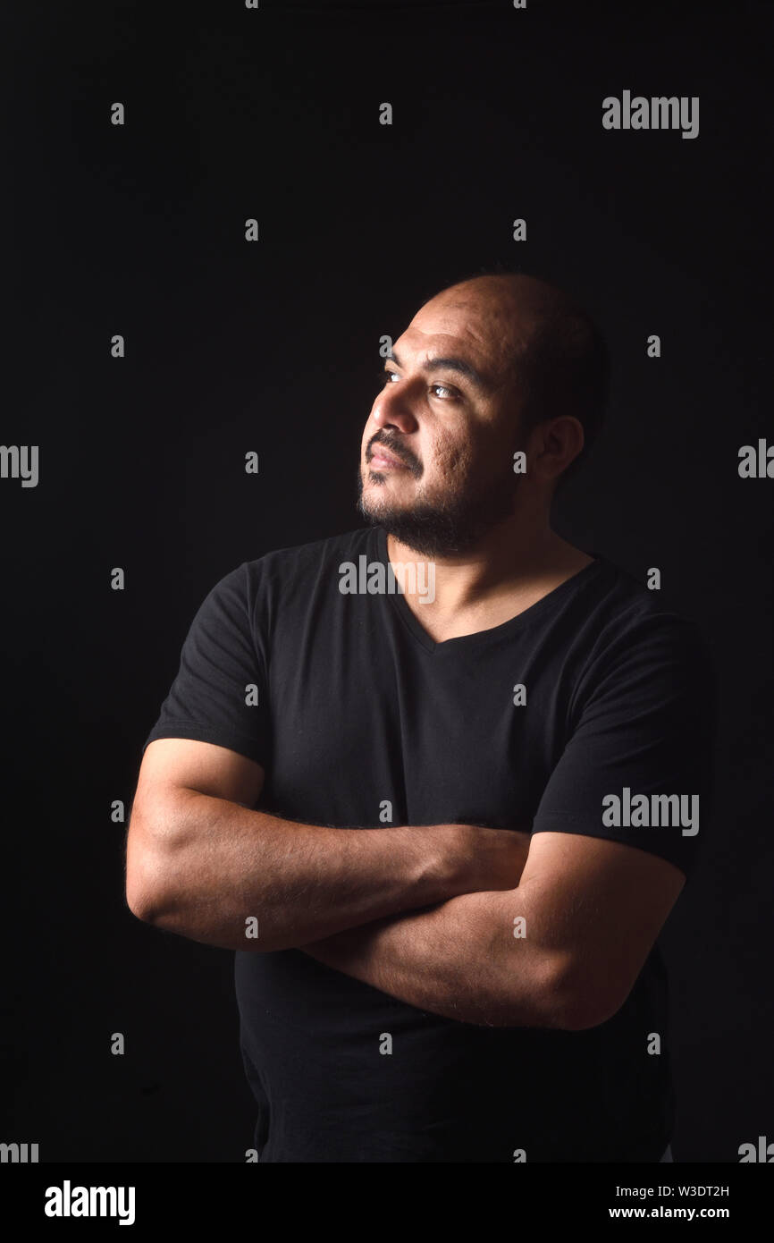 portrait of profile of a latin american man arms crossed on black ...