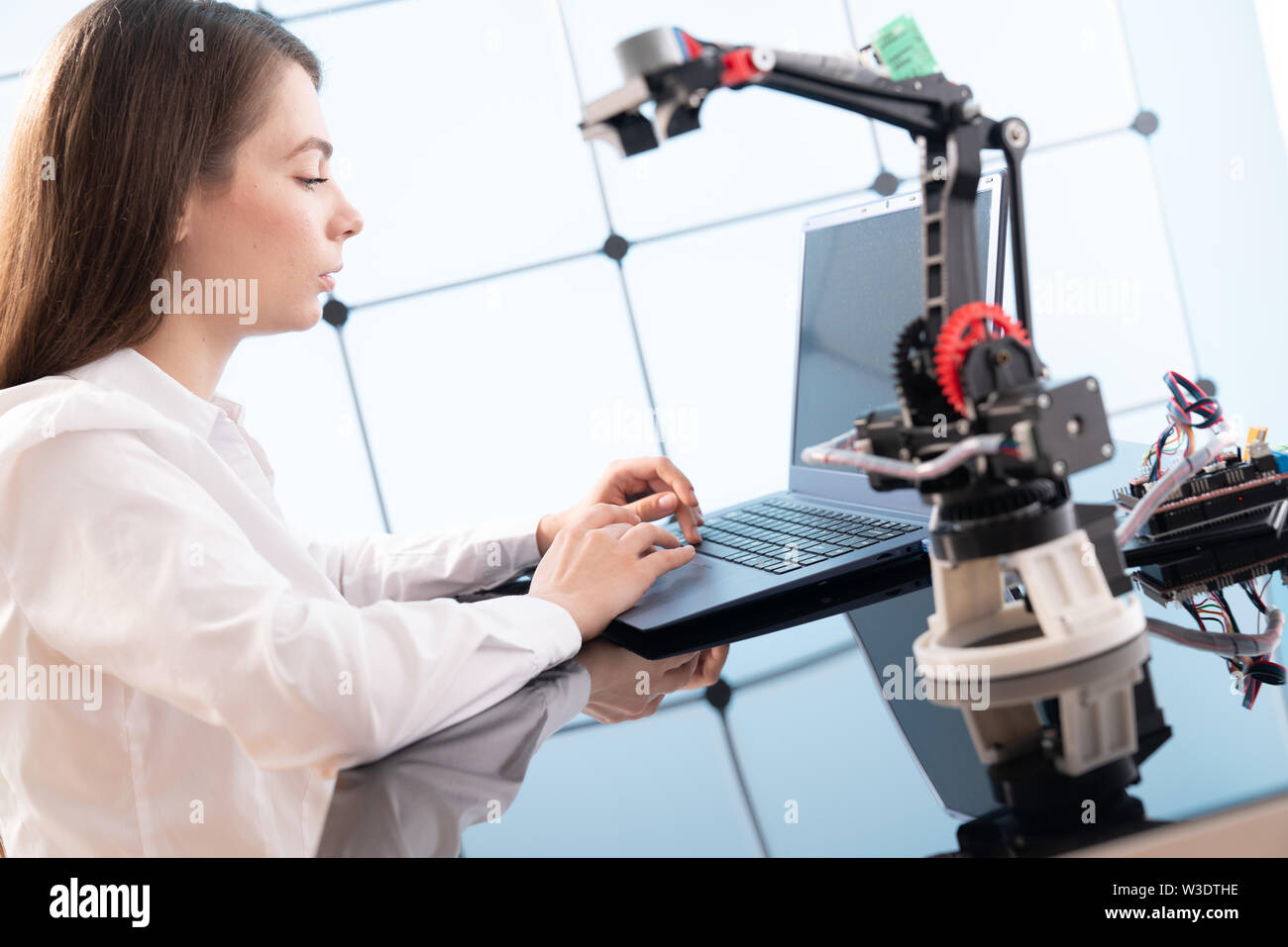 A young woman writes an algorithm for the robot arm. Science Research ...
