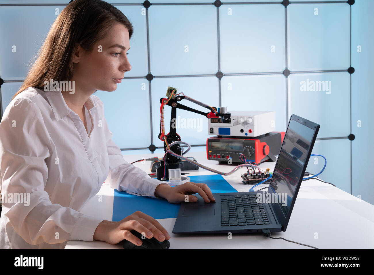 A young woman writes an algorithm for the robot arm. Science Research ...
