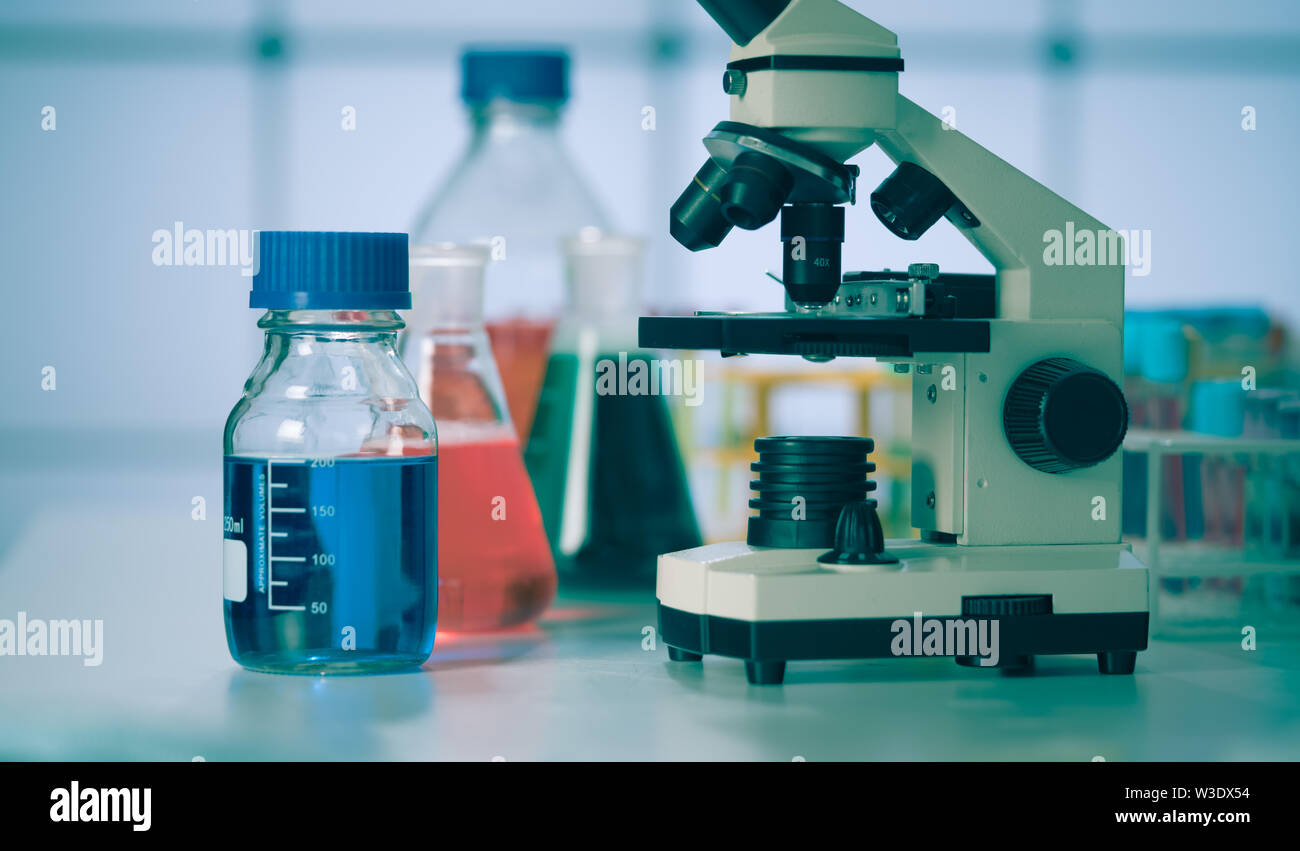 Microscope and test tubes on laboratoy table Stock Photo - Alamy