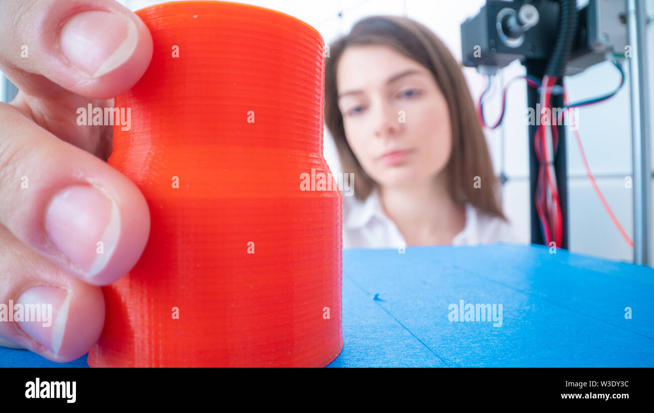Young women designer in 3d printing lab. Girl takes the finished detail ...