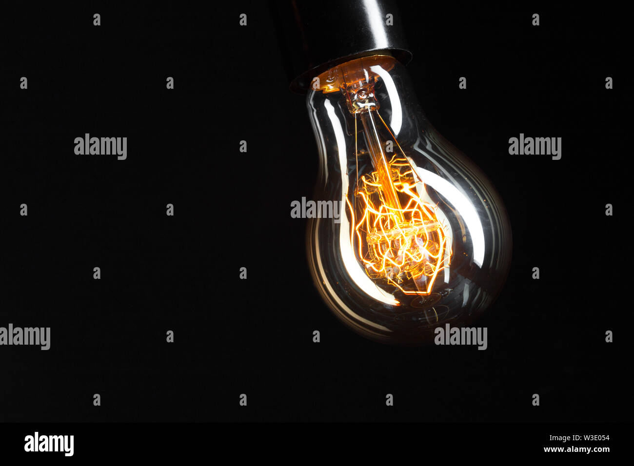 A classic Edison light bulb on dark background with space for text ...