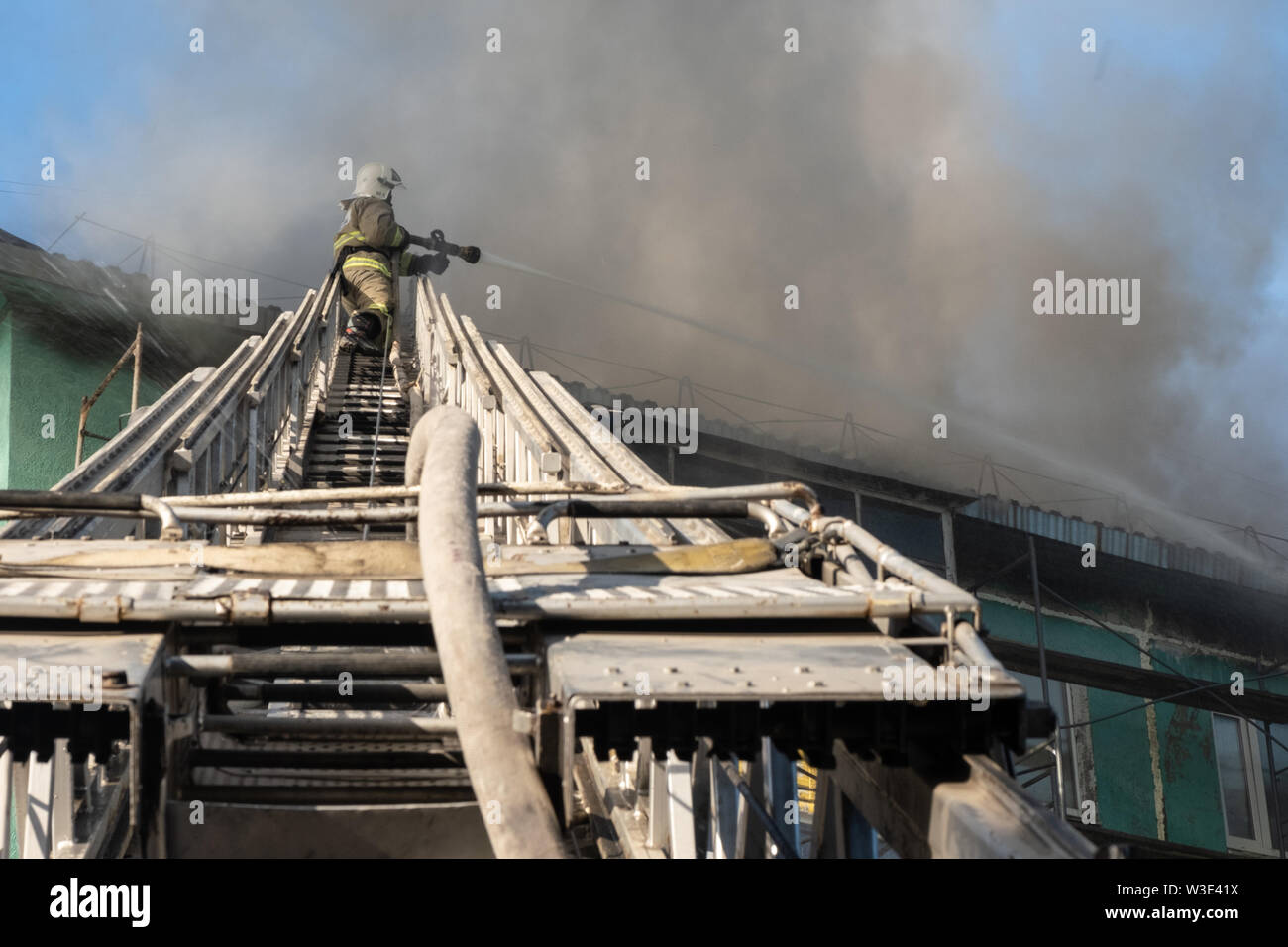Firefighters on the stairs extinguish a fire on the roof of a ...