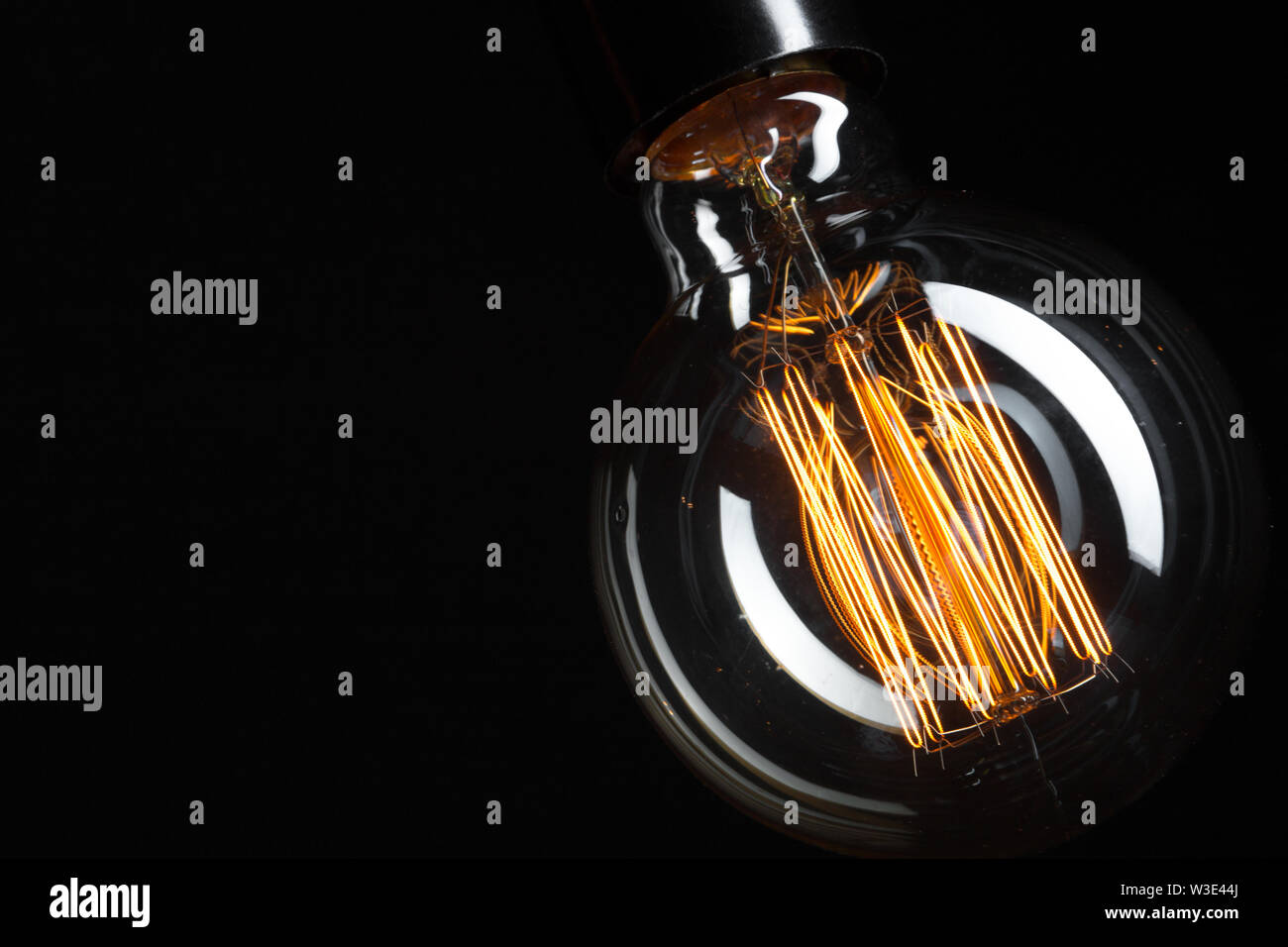A classic Edison light bulb on dark background with space for text ...