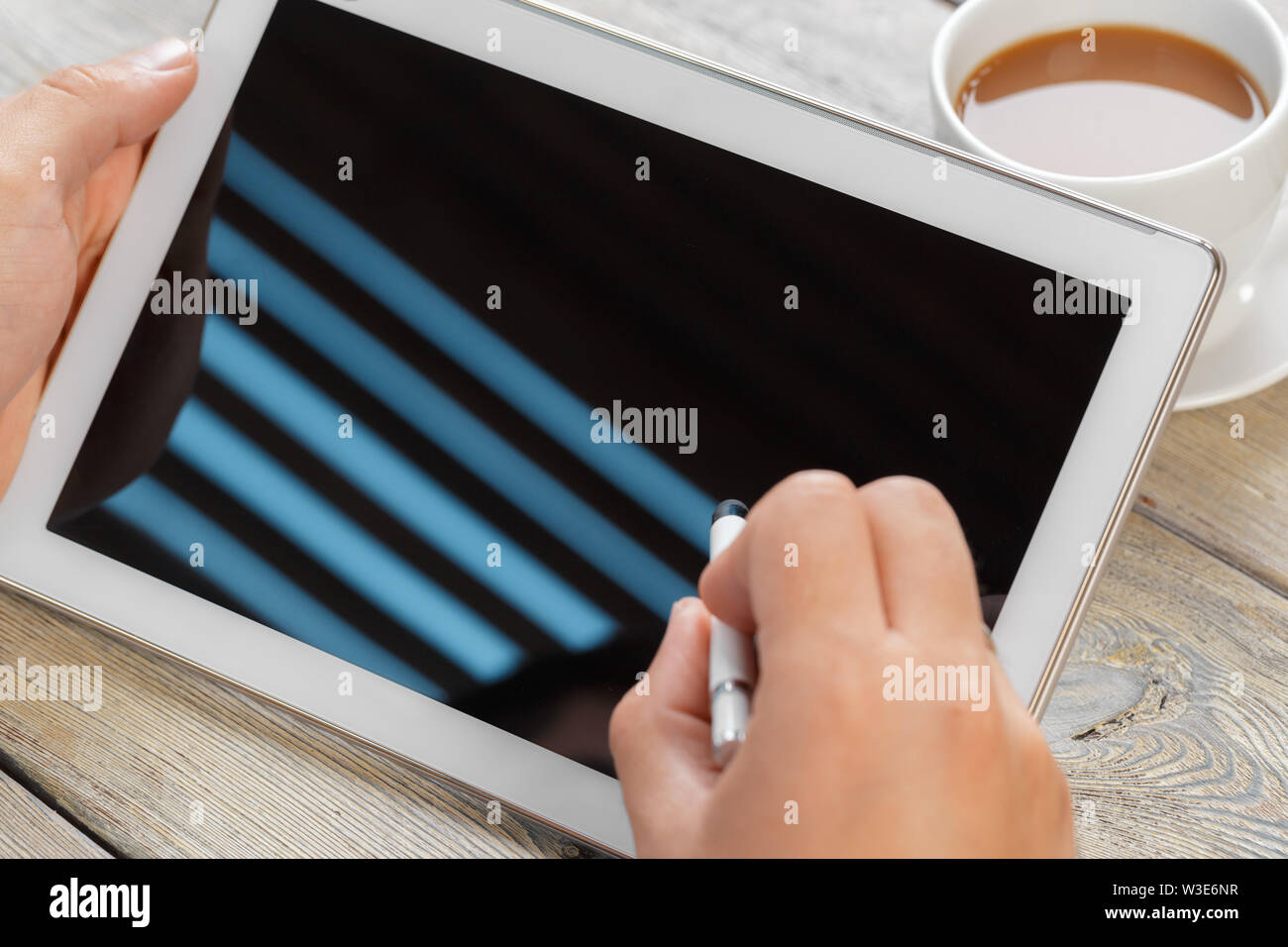 hands of a man holding blank tablet device over a wooden workspace ...