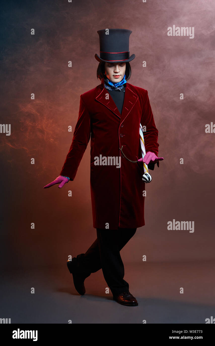 Fabulous circus man in a hat and a red suit posing in the smoke on a ...