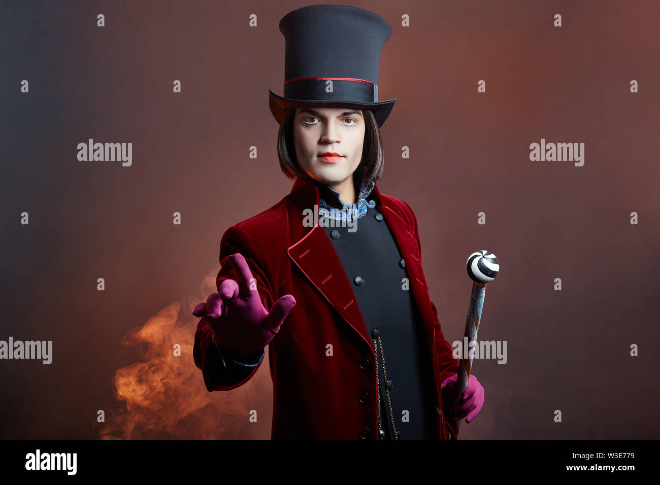 Fabulous circus man in a hat and a red suit posing in the smoke on a ...