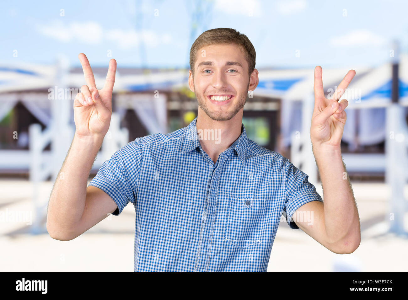 Attractive young man shows a sign of peace or victory Stock Photo - Alamy
