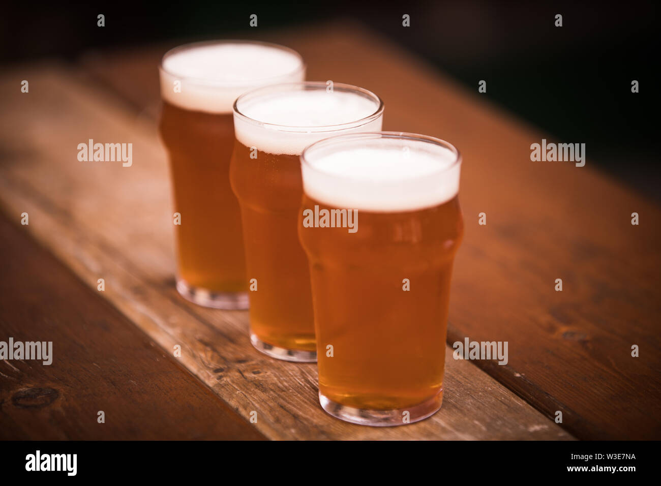 Three pints of beer in a row, on a table Stock Photo - Alamy