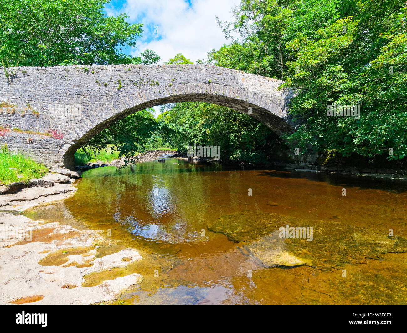 A bright summer day besides the River Ribble near an old stone bridge ...