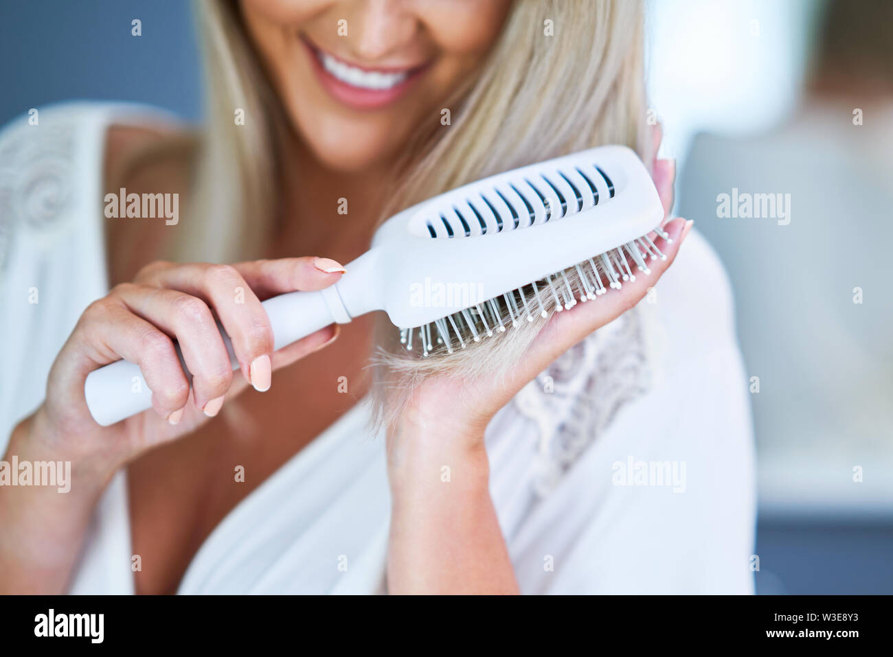 Adult woman brushing her hair in bathroom Stock Photo - Alamy