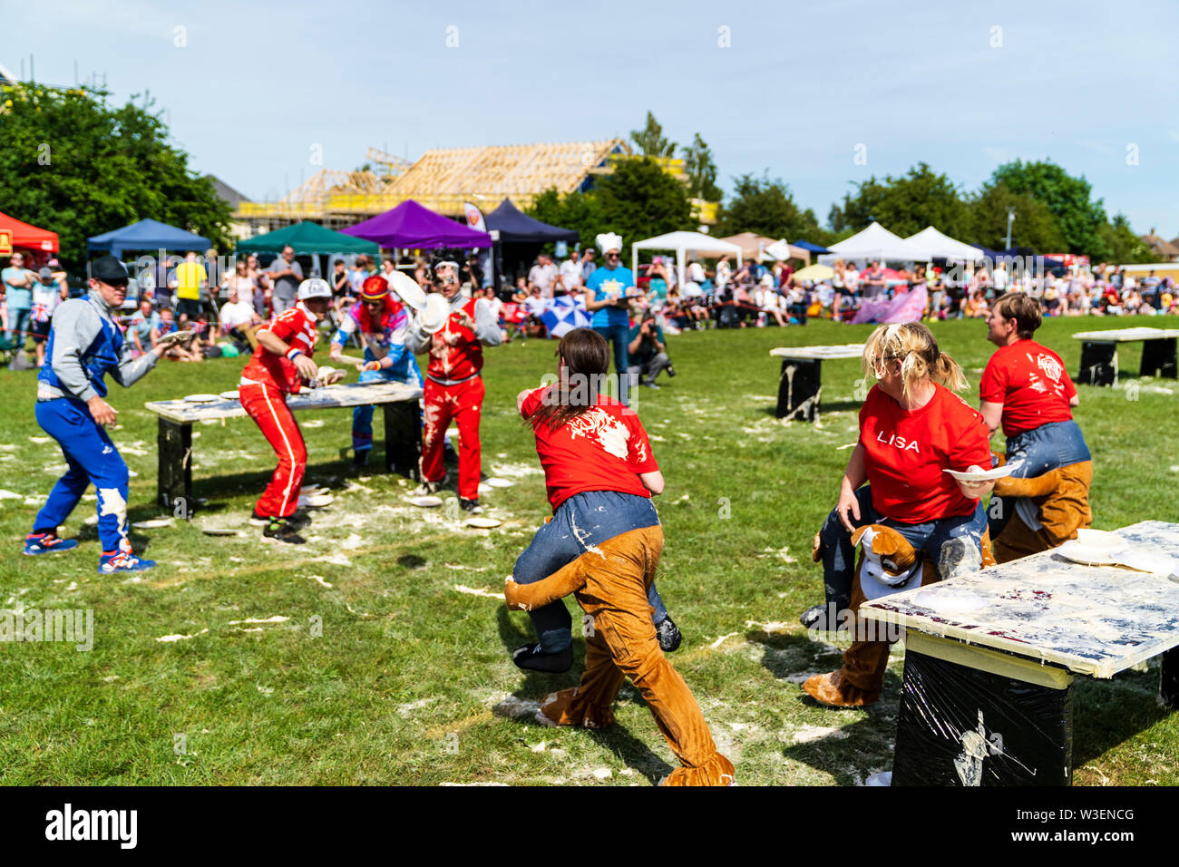 Two teams in fancy dress in field with audience watching, throwing ...