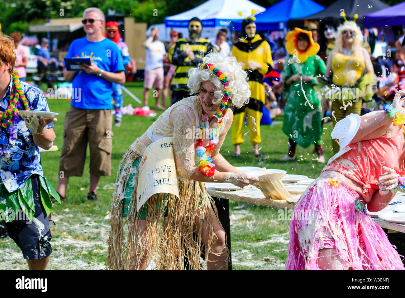 Custard covered young woman team member throwing custard pie at unseen ...