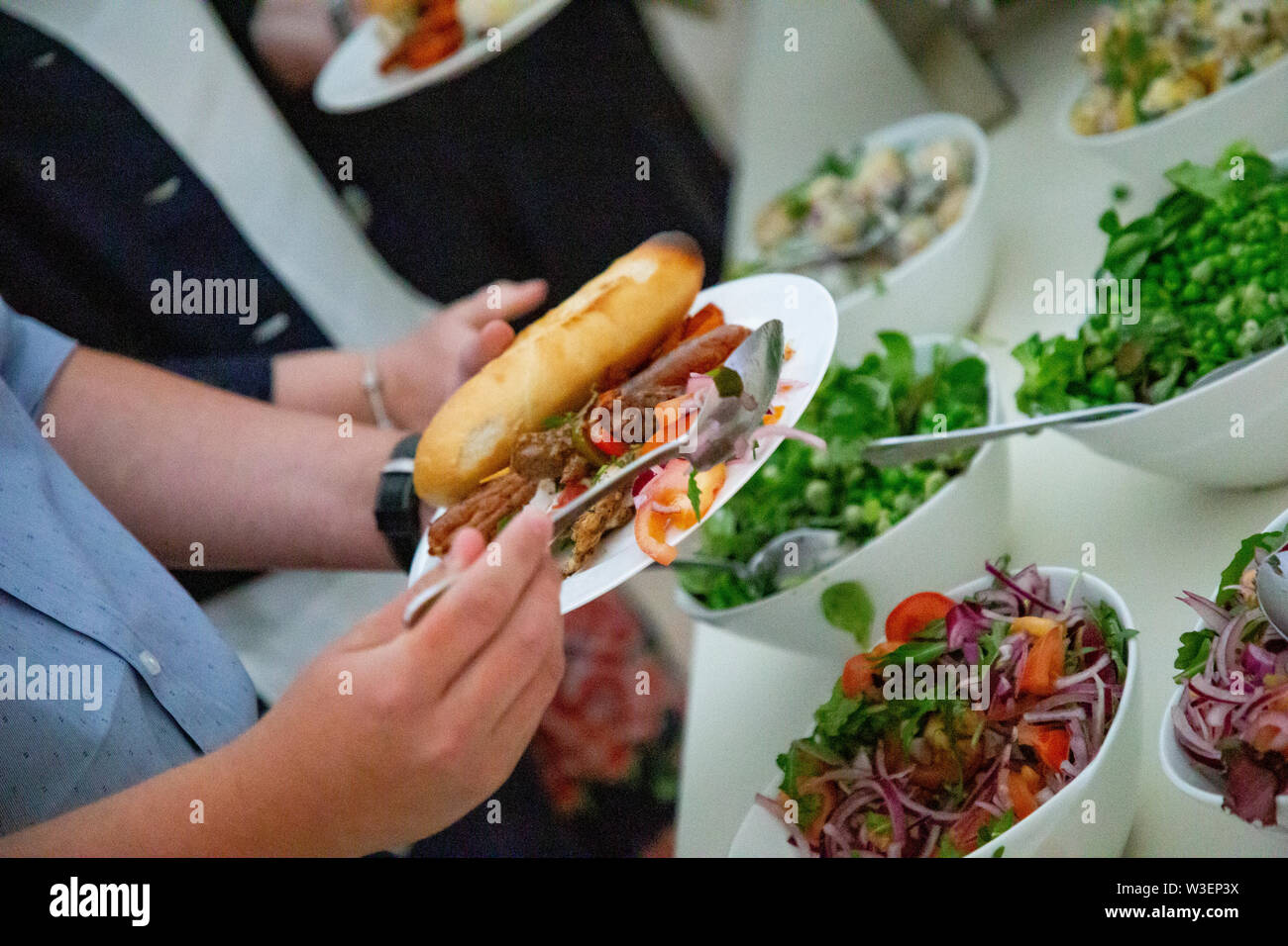 Wedding guest adding salad to plate of food Stock Photo - Alamy