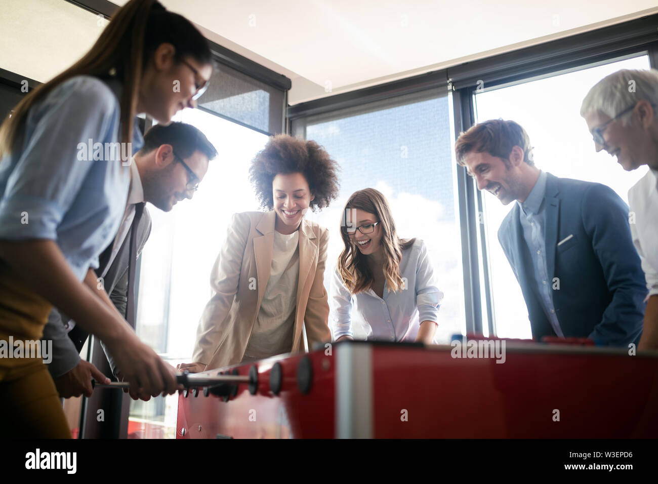 Employees playing table soccer indoor game in the office during break ...