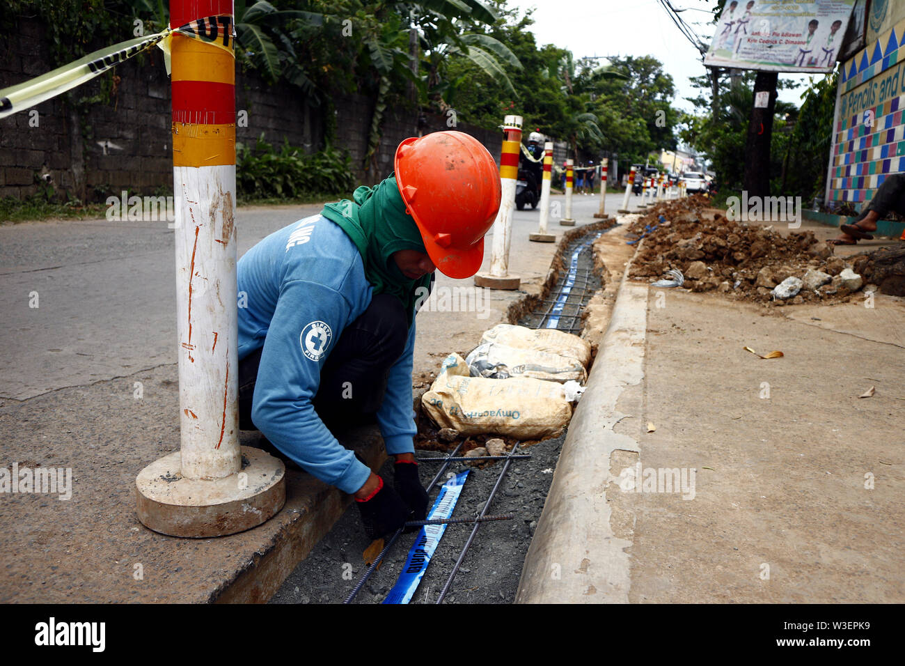 ANTIPOLO CITY, PHILIPPINES – JULY 12, 2019: A construction worker lays ...