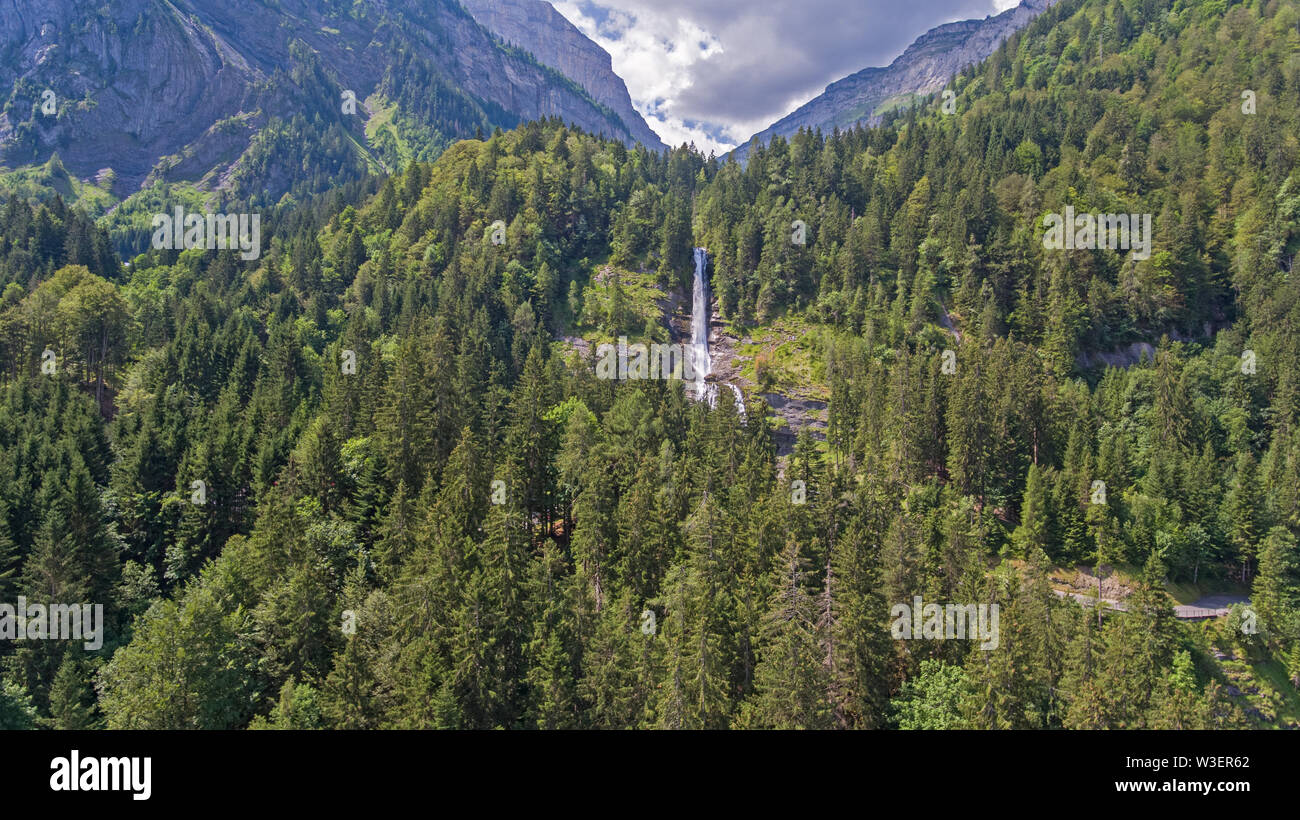 drone view of a alpine river valley and lush green alpine forests ...