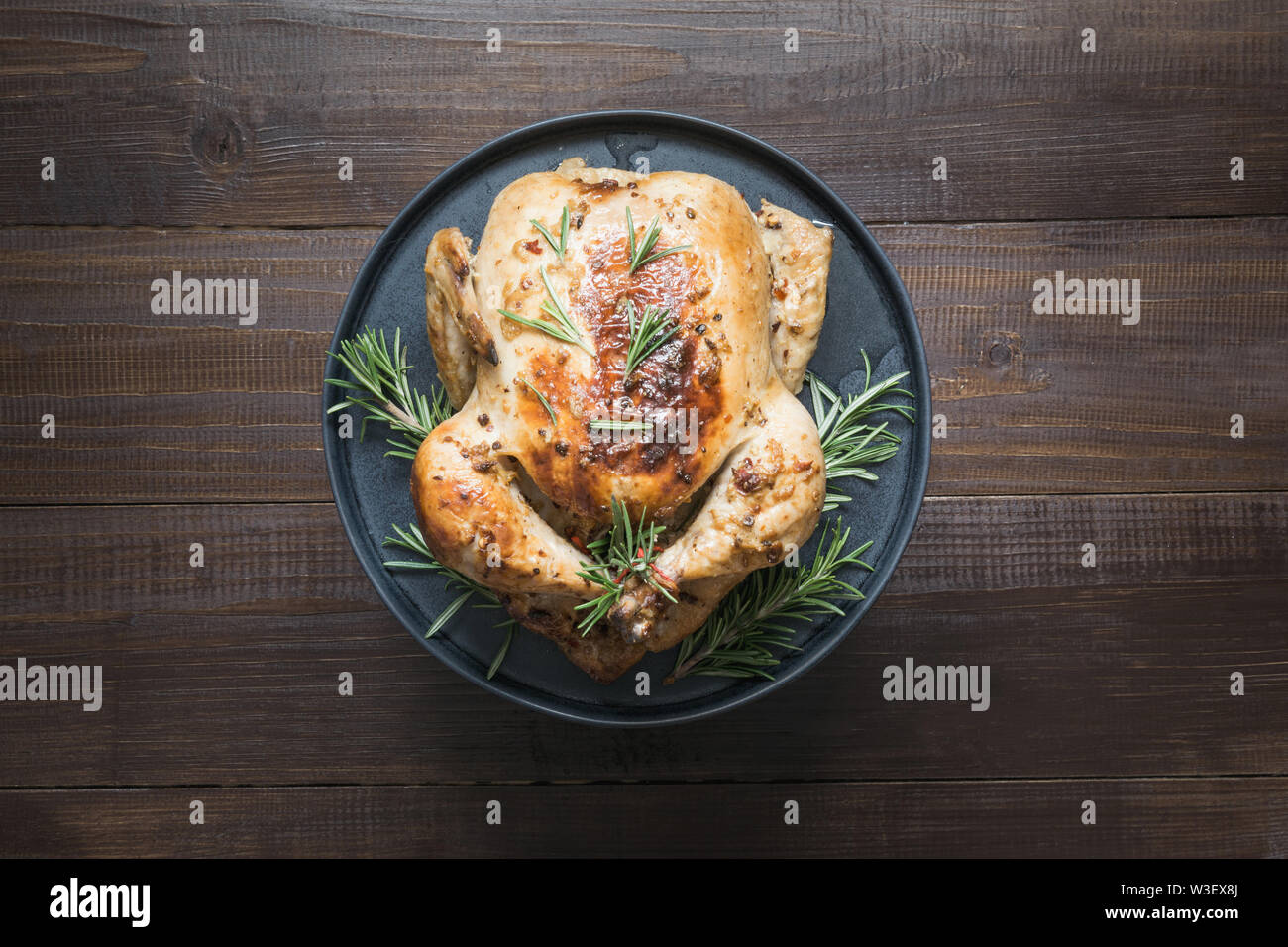 Traditional roasted turkey garnish rosemary in female hand on dark ...