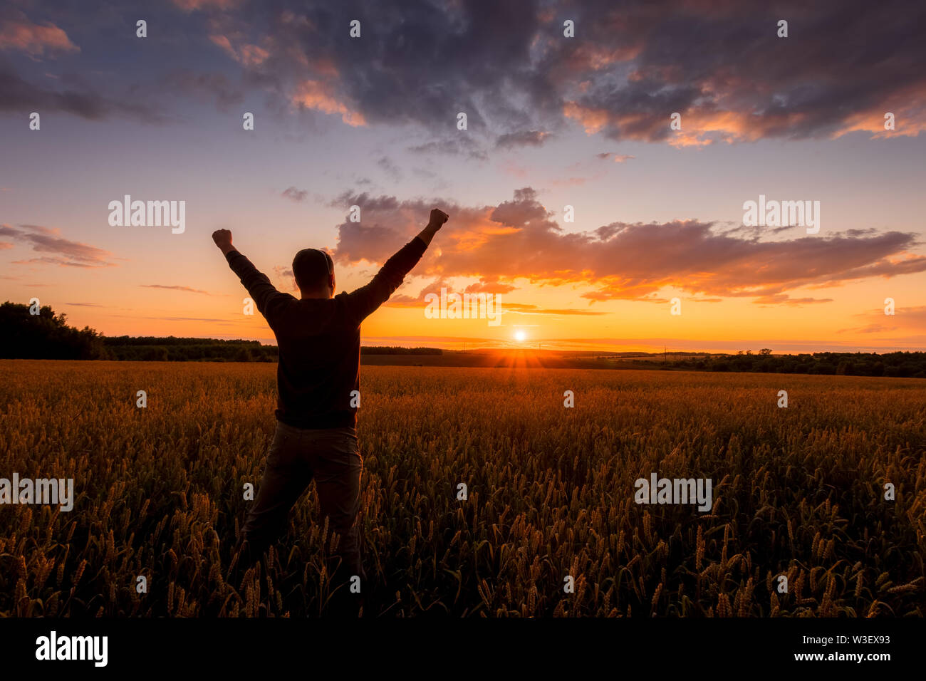 Silhouette of a man raise his hands up to sunset on the field with ...