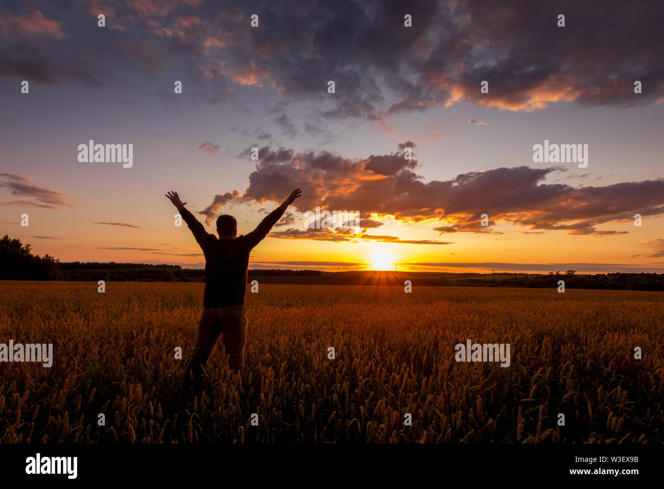 Silhouette of a man raise his hands up to sunset on the field with ...