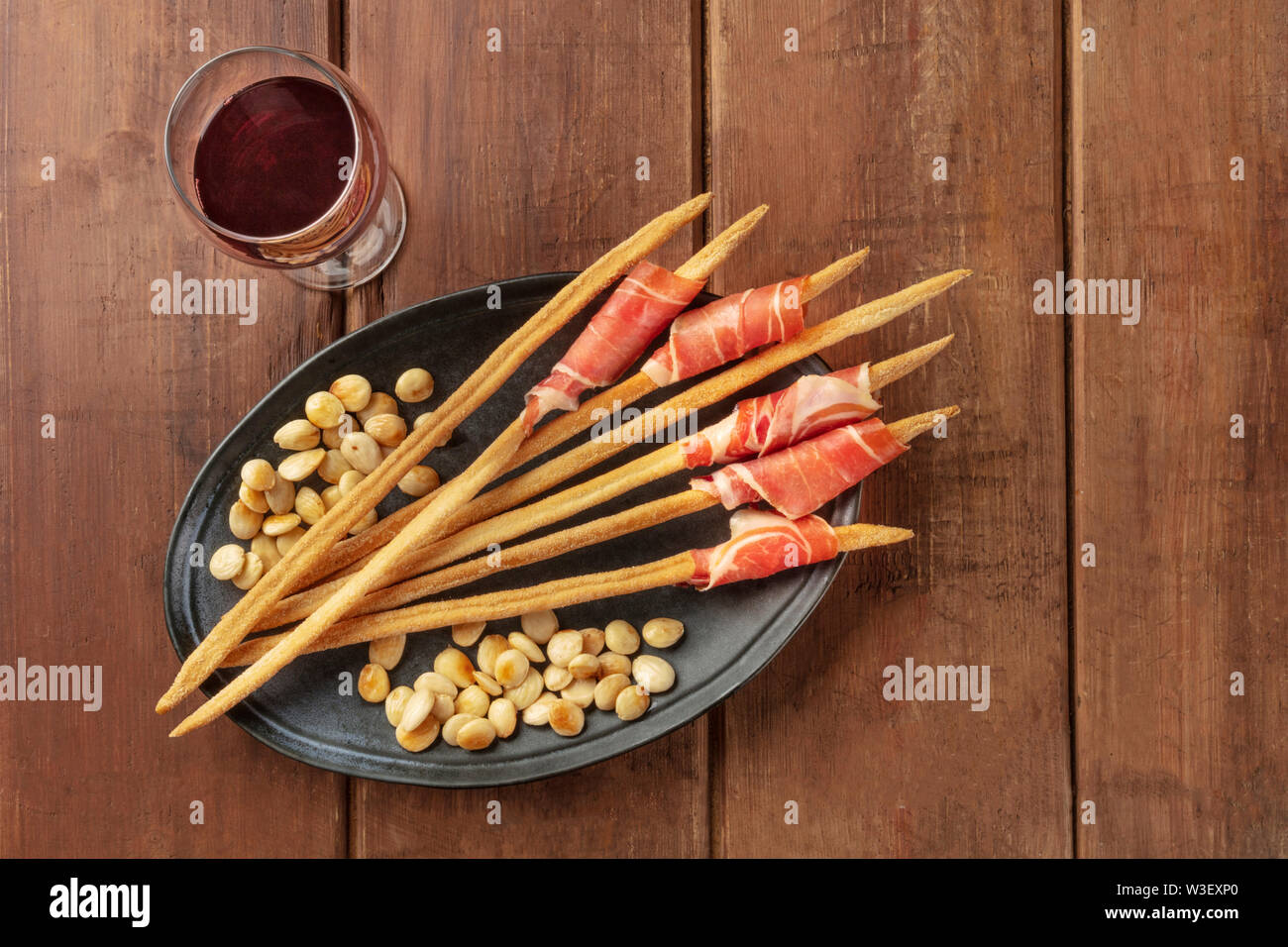 Prosciutto-wrapped Italian grissini with wine and roasted almonds, top ...