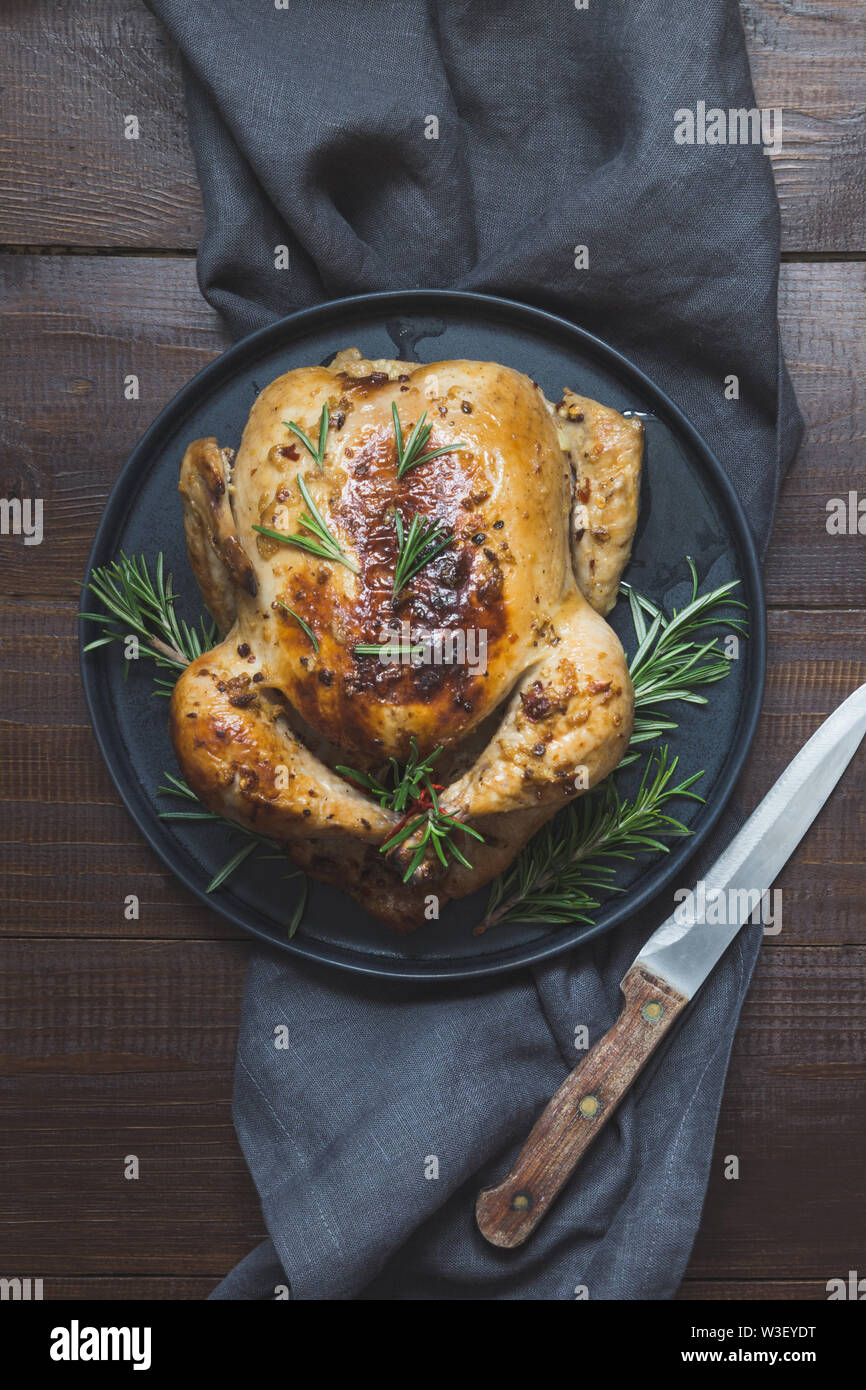 Traditional roasted turkey garnish rosemary in female hand on dark ...