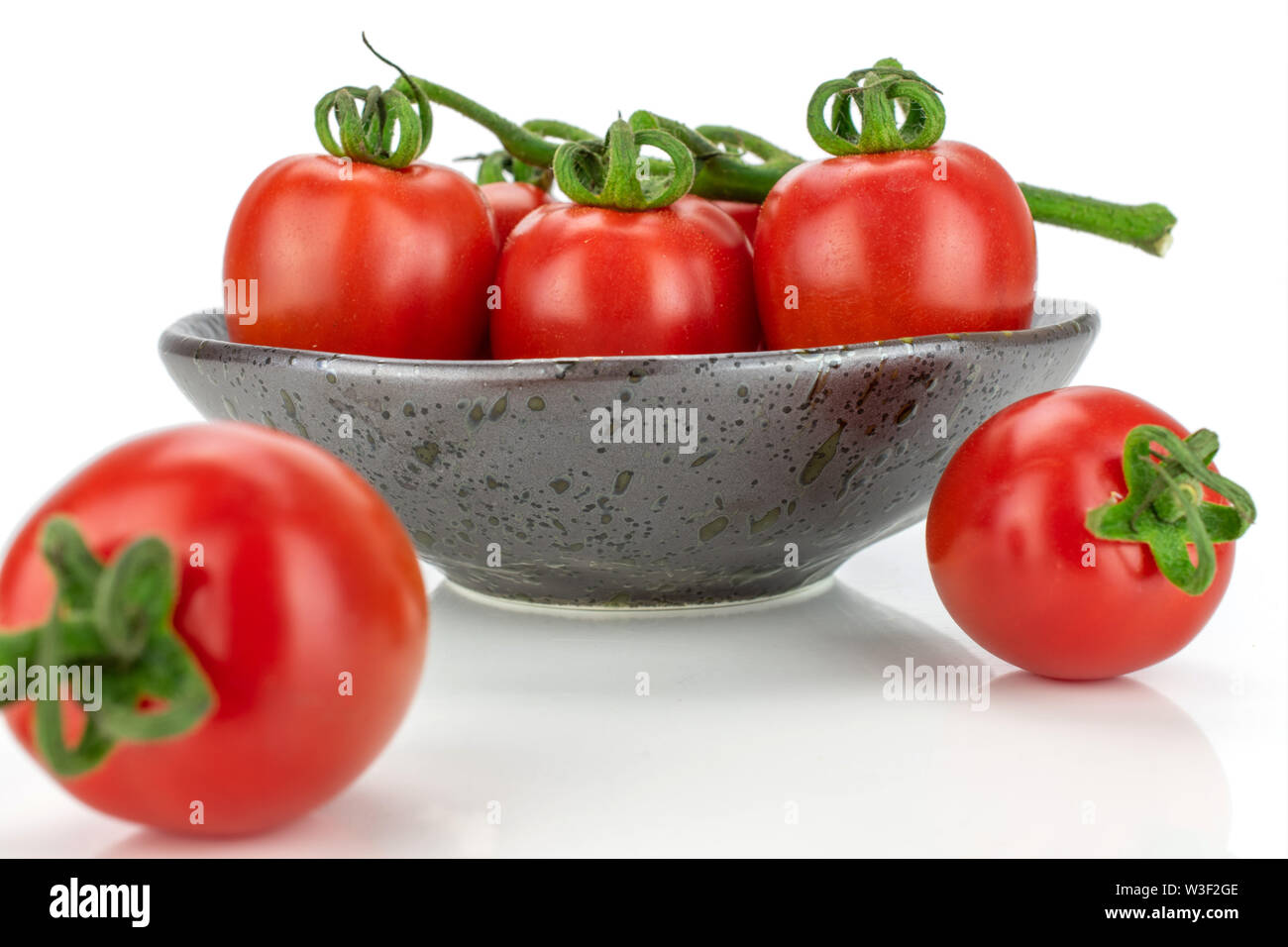 Group of seven whole fresh red tomato cherry back focus on a ceramic ...