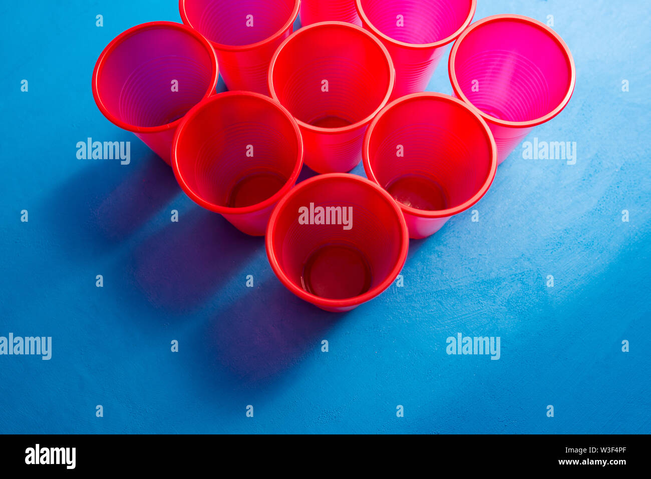 Colored plastic cups are a triangle on a blue background. Composition ...
