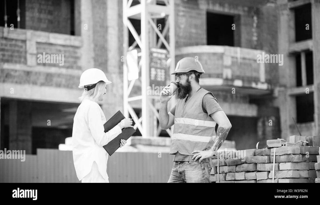 Woman engineer and brutal builder communicate construction site ...