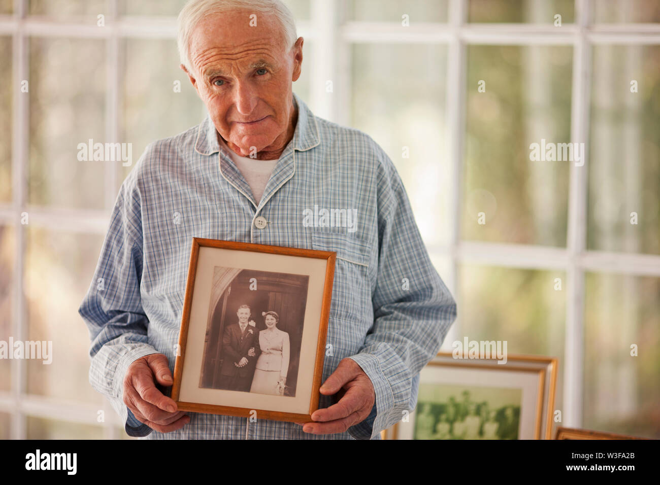 Portrait of a senior man holding a family photo in a picture frame ...