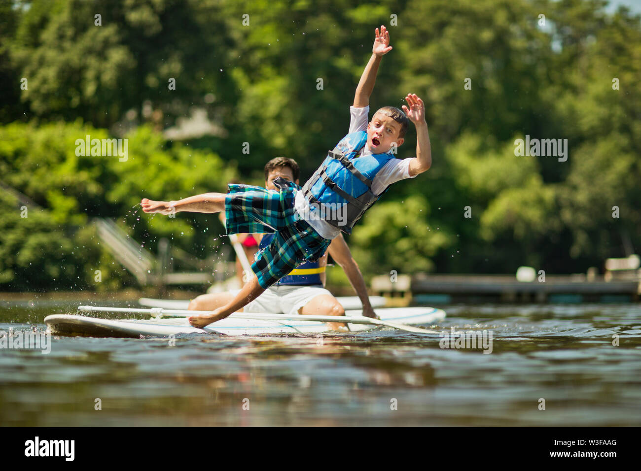 Happy young boy playfully falling off a paddleboard Stock Photo - Alamy