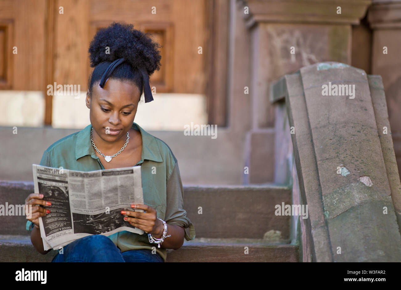 Young woman reading a newspaper on her front stoop Stock Photo - Alamy