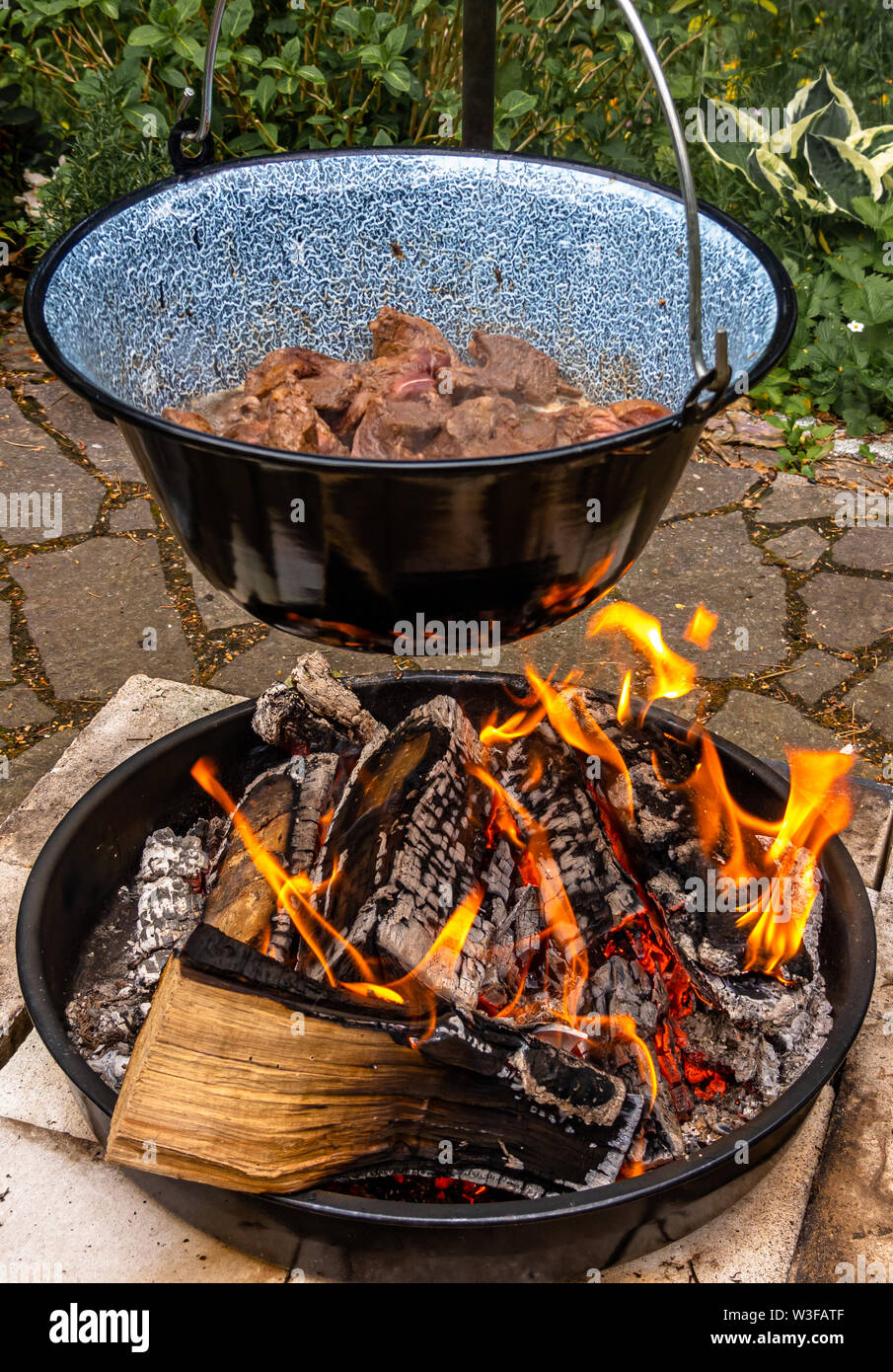 Frying the beef in a cauldron over an open wood fire to prepare the ...