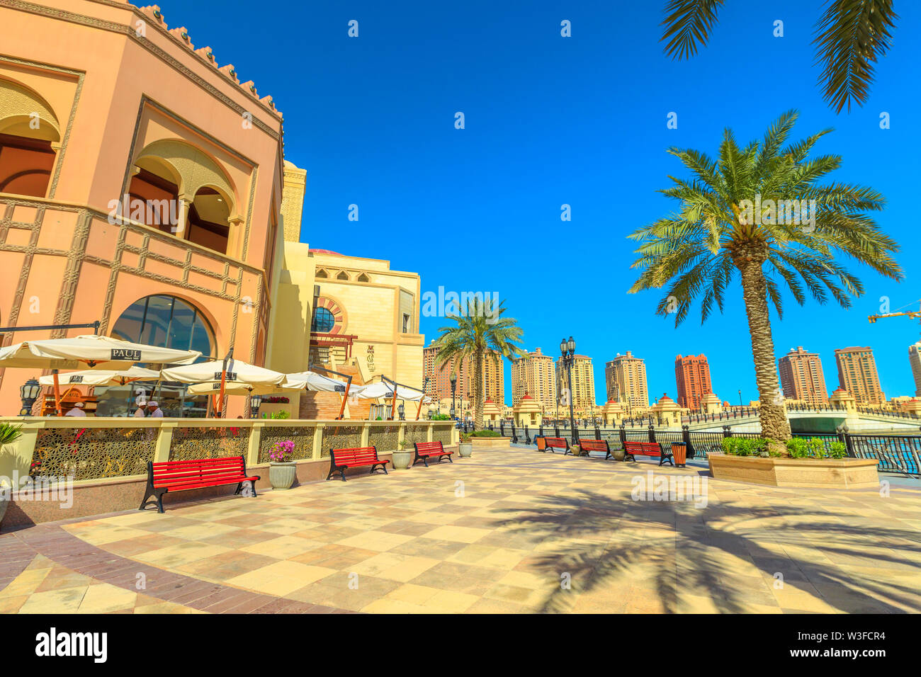 Doha, Qatar - February 18, 2019: benches and palm trees along marina ...