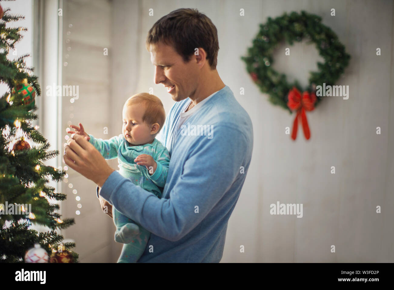 Happy father decorating a Christmas tree with his baby daughter Stock ...