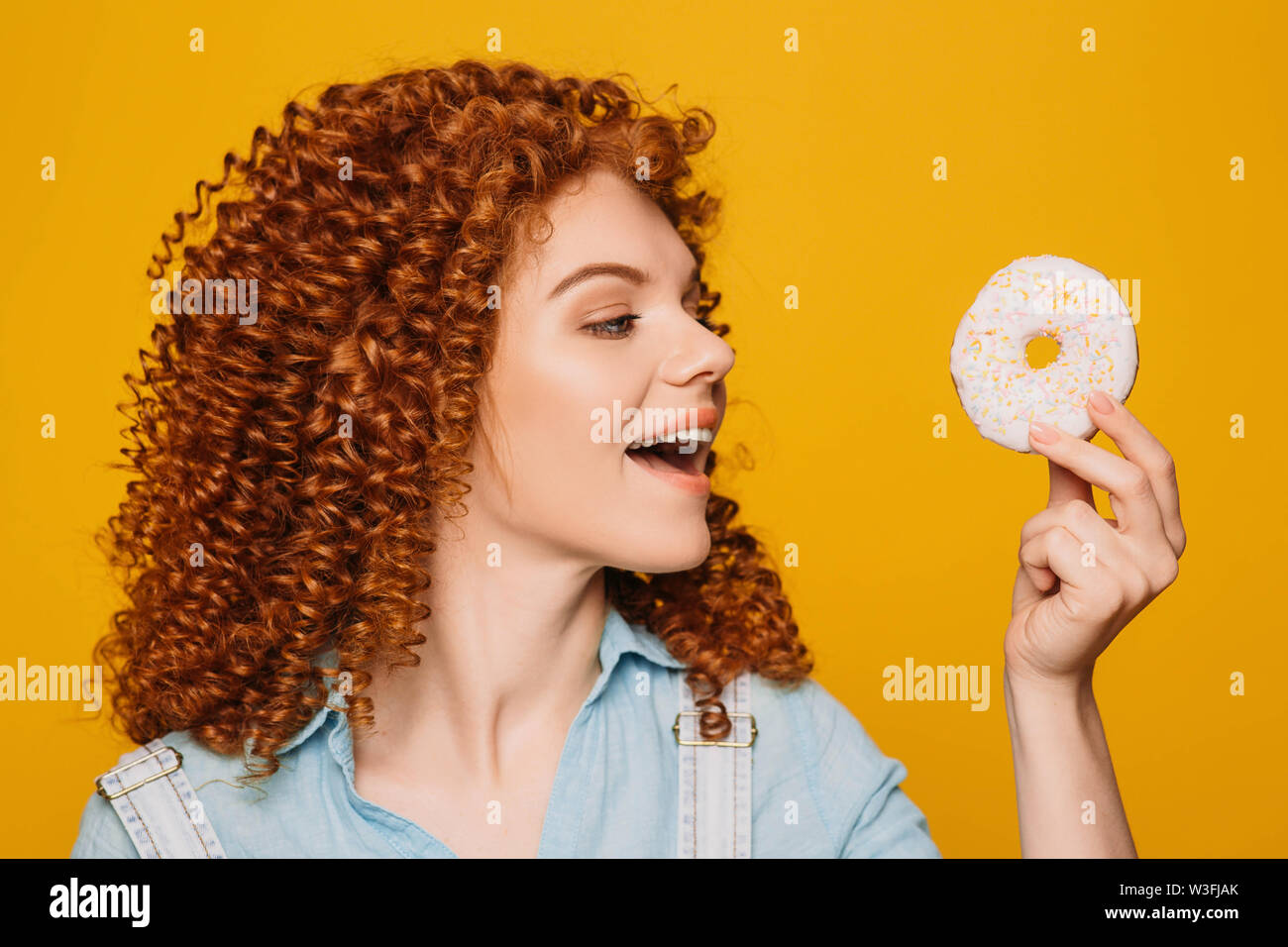 curly red-haired woman holding doughnut want to eating sweet doughnut ...