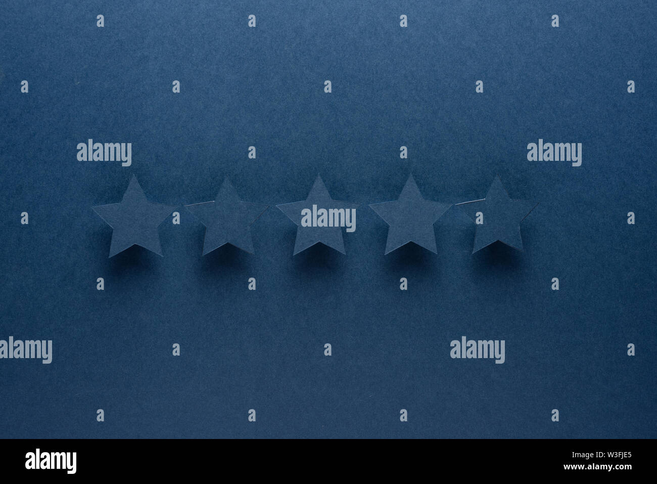 Feedback concept. Five blue paper stars of approval on a blue ...