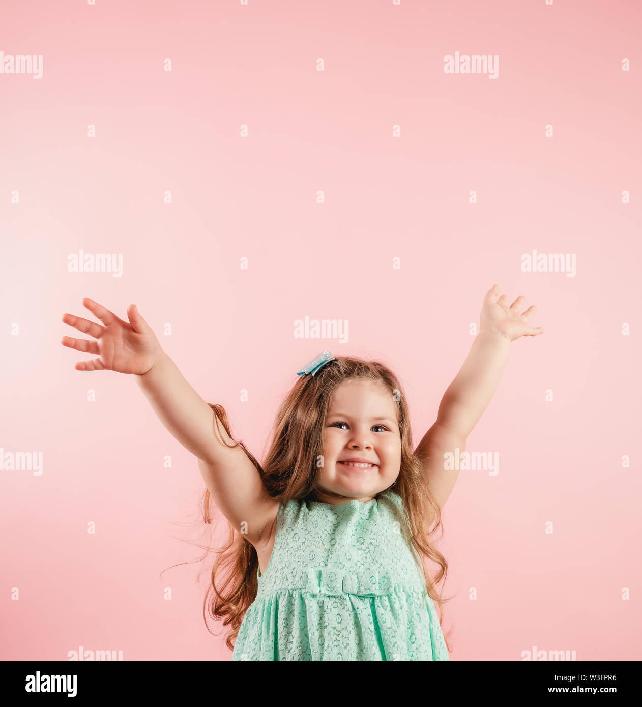 Cheerful little girl open hands against pink background Stock Photo - Alamy