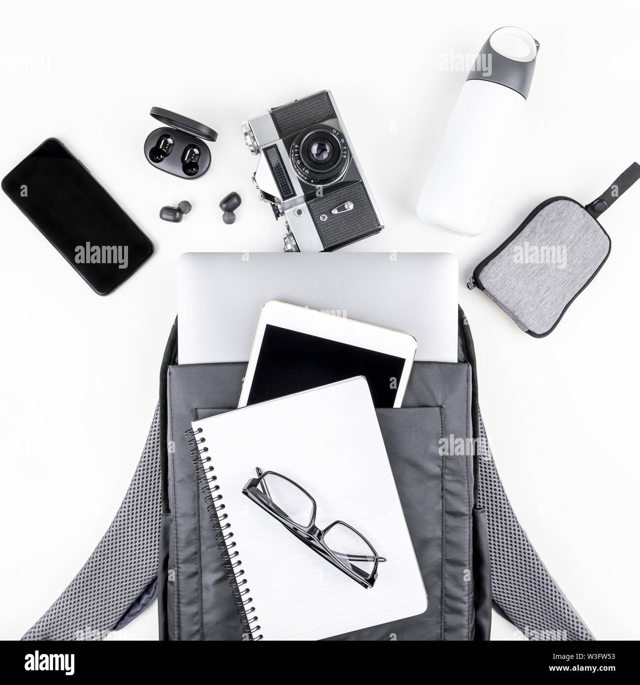 Creative top view flat lay of open backpack with laptop and tablet ...