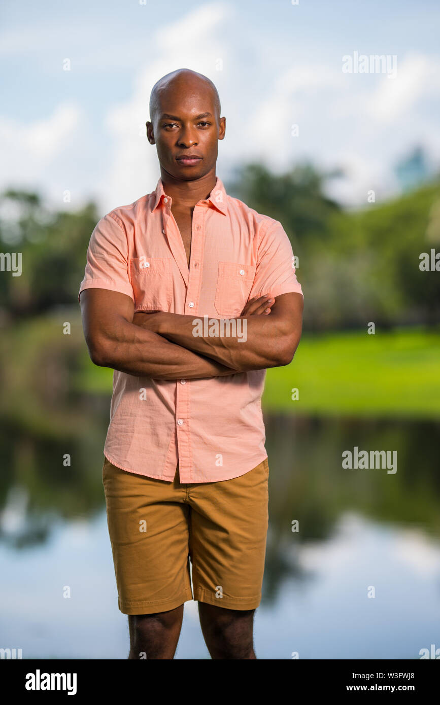 Man posing in a pink button shirt with arms crossed. African American ...