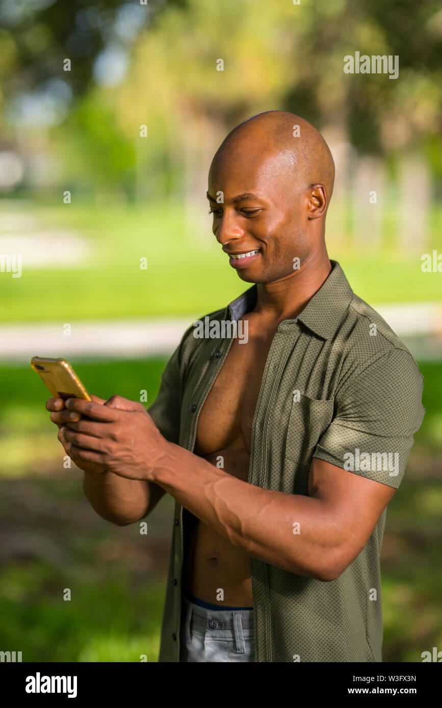 Photo of a handsome black man sending a text message on his smartphone ...