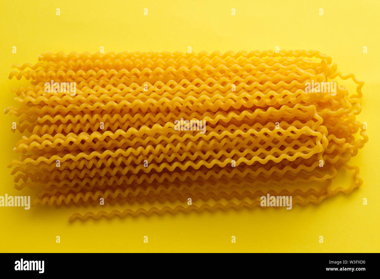 Raw fusilli lunghi pasta over yellow background.jpg Stock Photo - Alamy